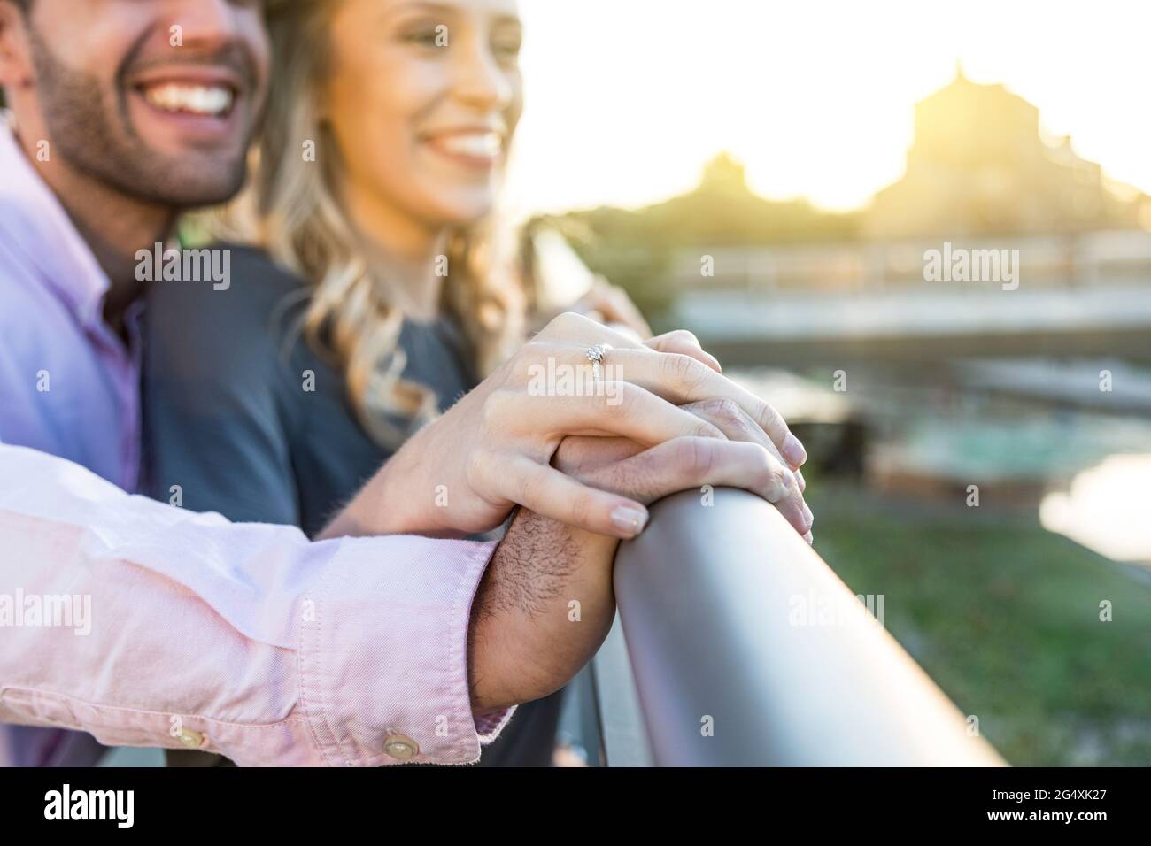 Boyfriend and girlfriend standing at railing during sunset Stock Photo ...