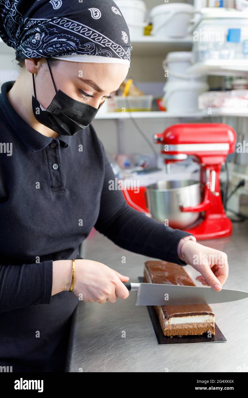 Female owner cutting slice of cake in bakery Stock Photo - Alamy