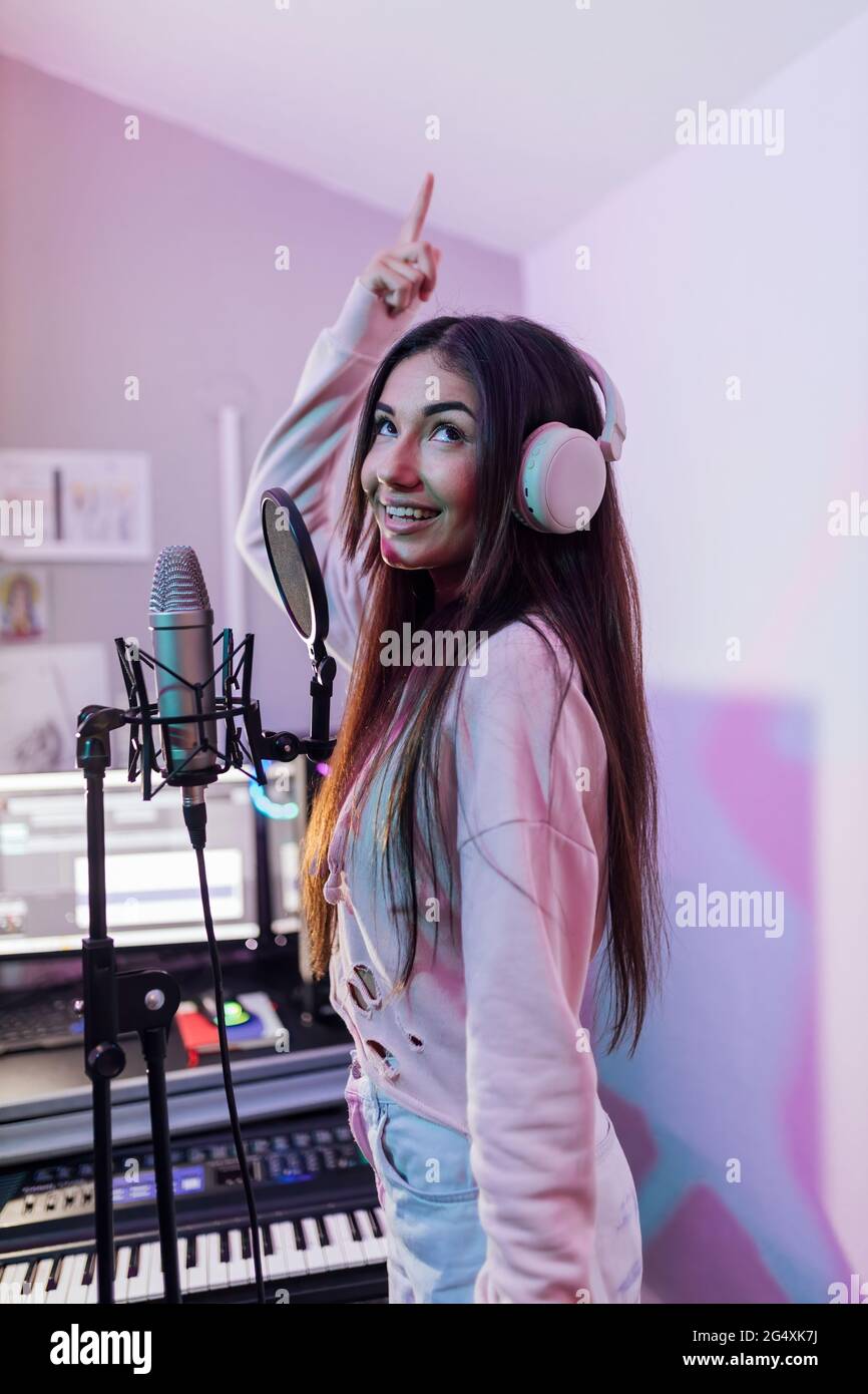 Female singer looking up while singing with hand raised at studio Stock ...