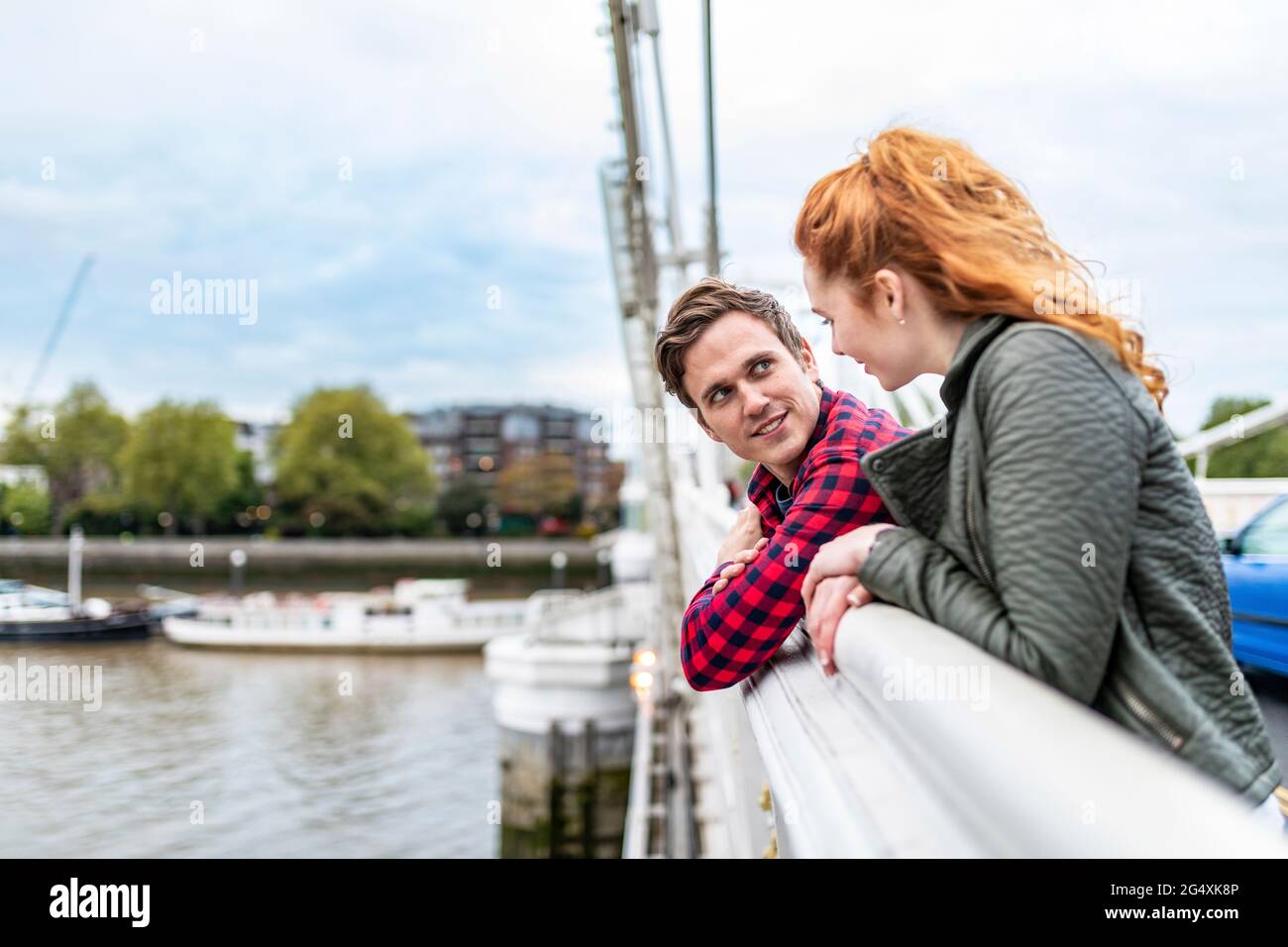 Man looking at girlfriend while leaning on railing at bridge Stock ...