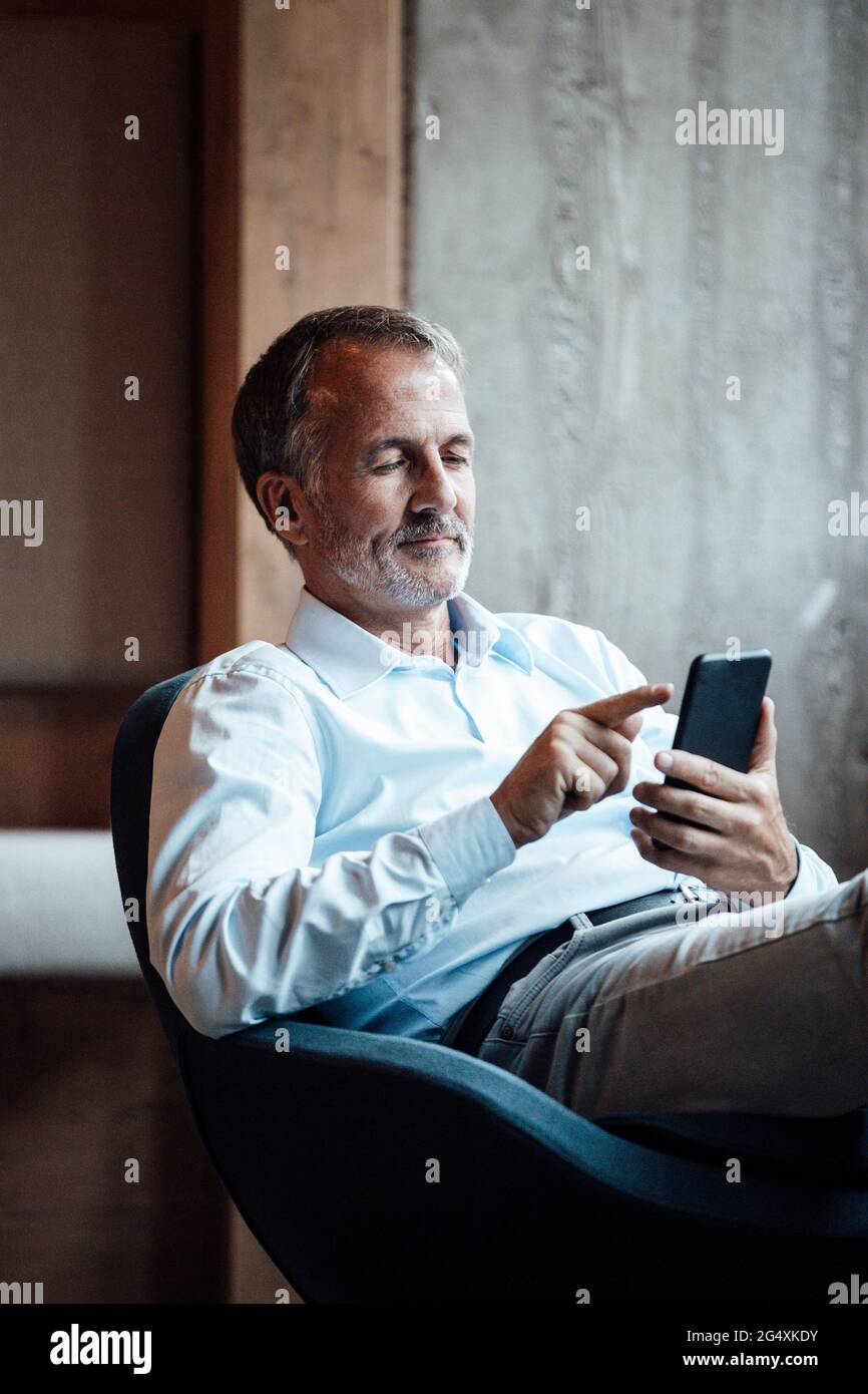 Male professional using smart phone while sitting on chair Stock Photo ...