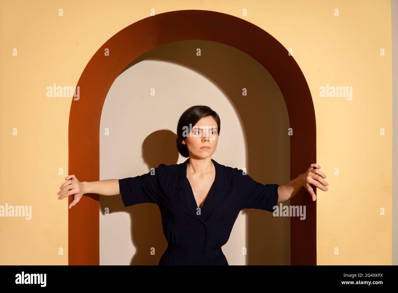 Young woman standing under arch Stock Photo - Alamy