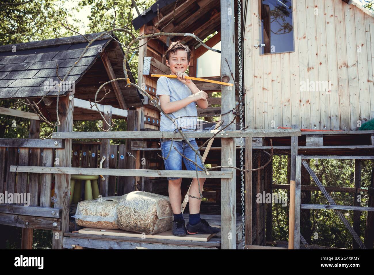 Smiling boy holding work tool in wooden rabbit hutch Stock Photo - Alamy