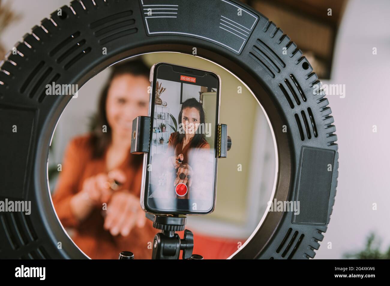 Female influencer using foundation while vlogging at home Stock Photo ...