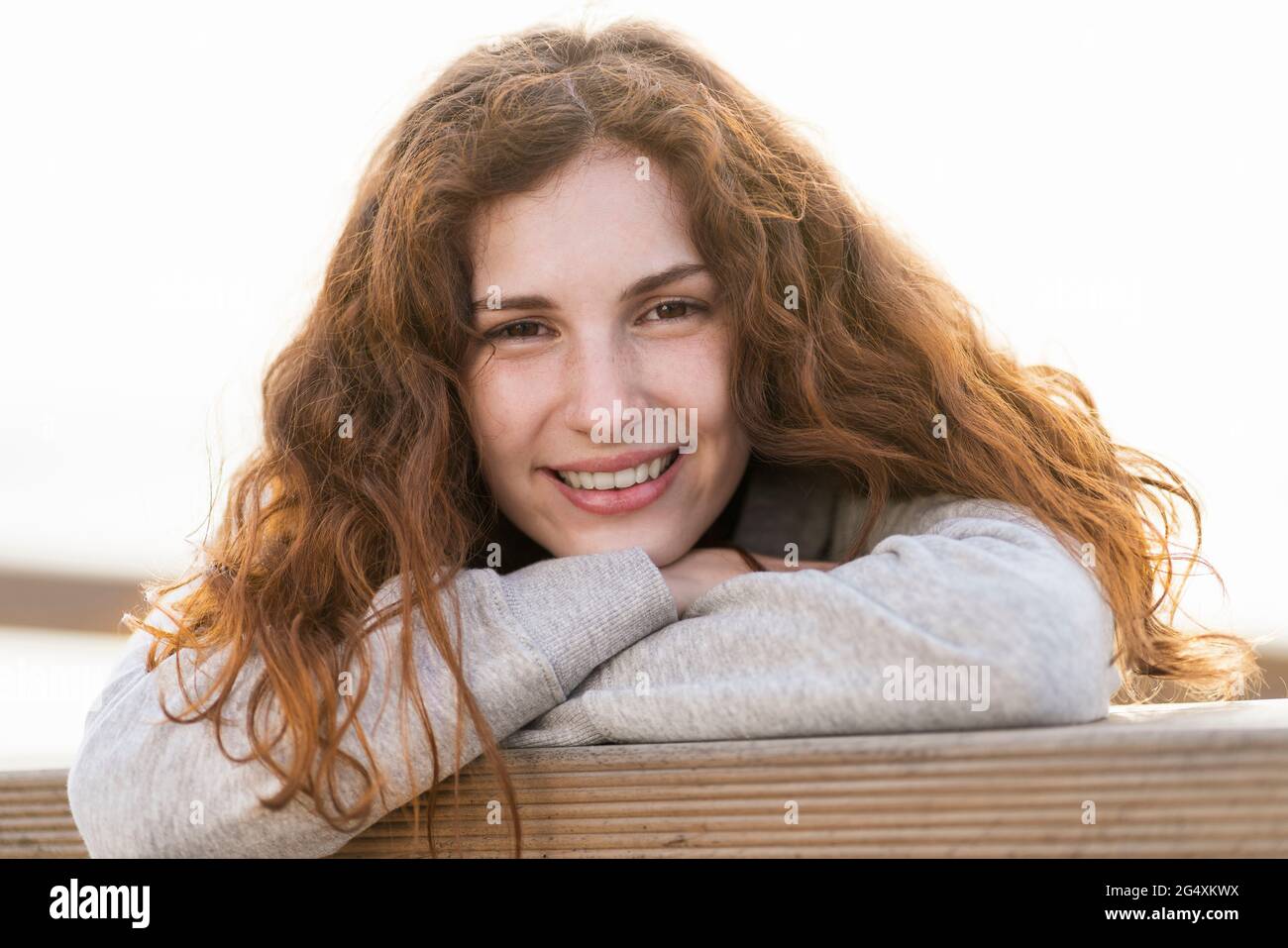 Beautiful smiling woman with arms crossed leaning on railing Stock ...