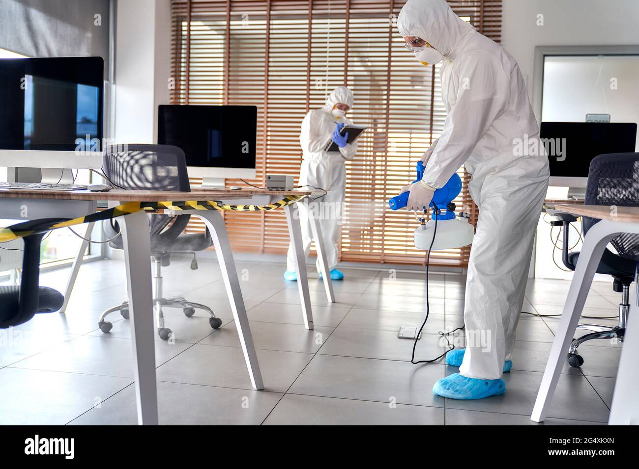 Sanitation worker spraying disinfecting chemical at office Stock Photo ...