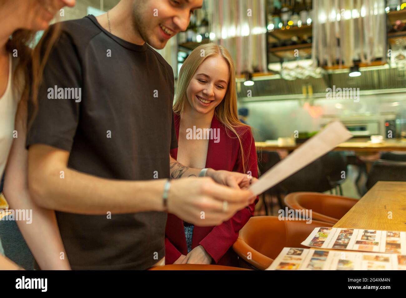 Smiling male and female friends reading menu at bar Stock Photo - Alamy
