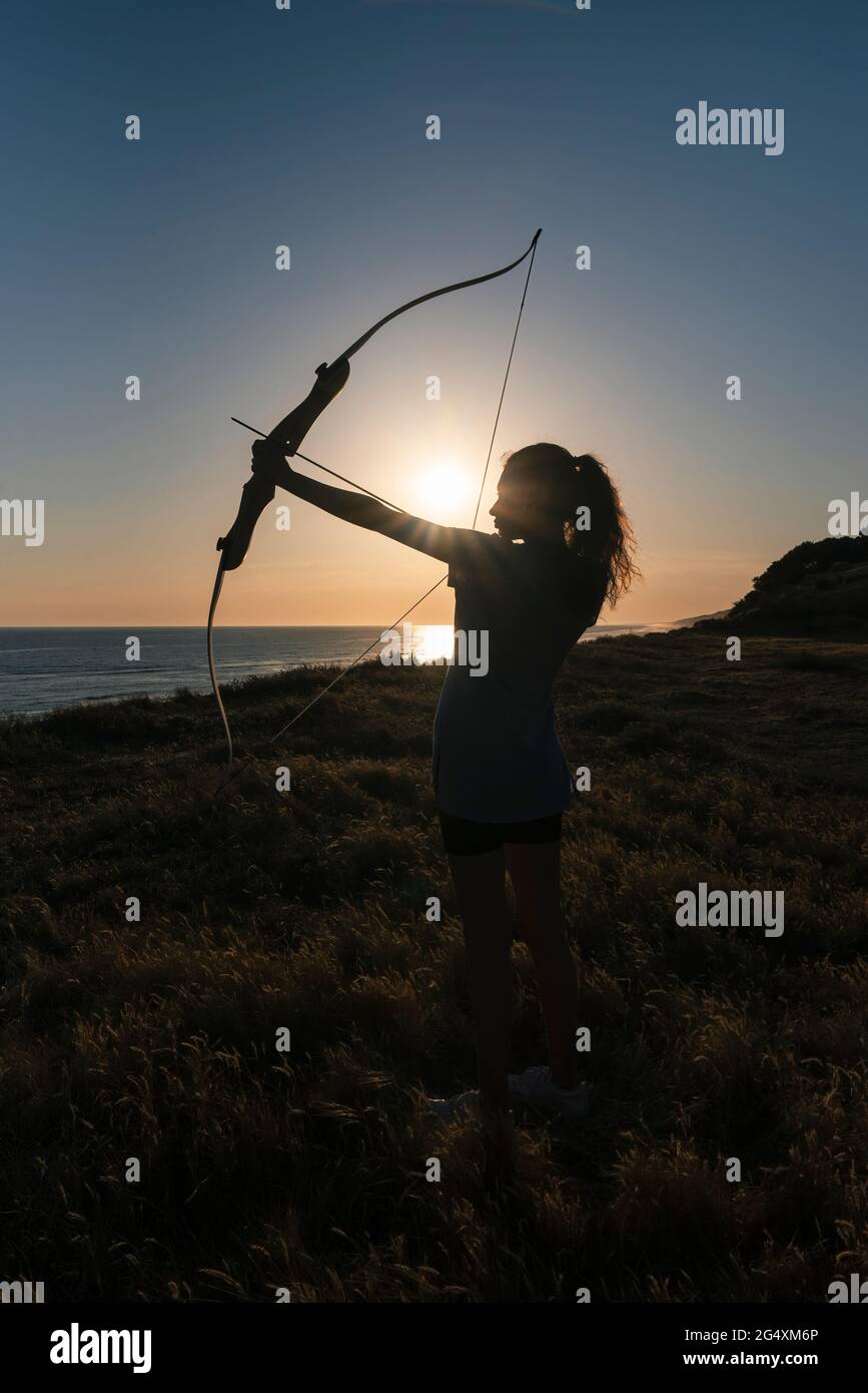 Young woman holding bow arrow hi-res stock photography and images - Alamy