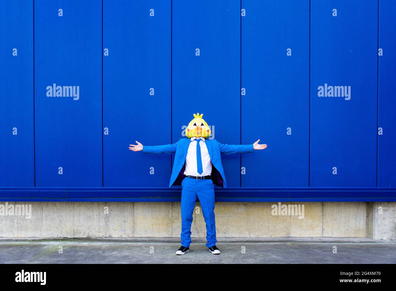Man wearing vibrant blue suit and bird mask standing outdoors with open ...