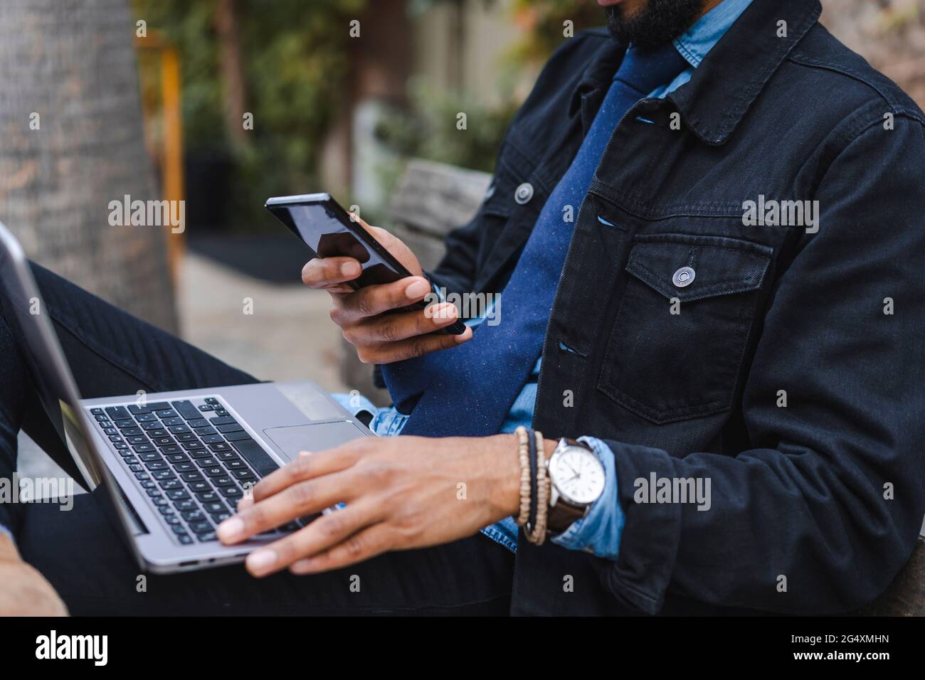Male entrepreneur with laptop using mobile phone Stock Photo - Alamy