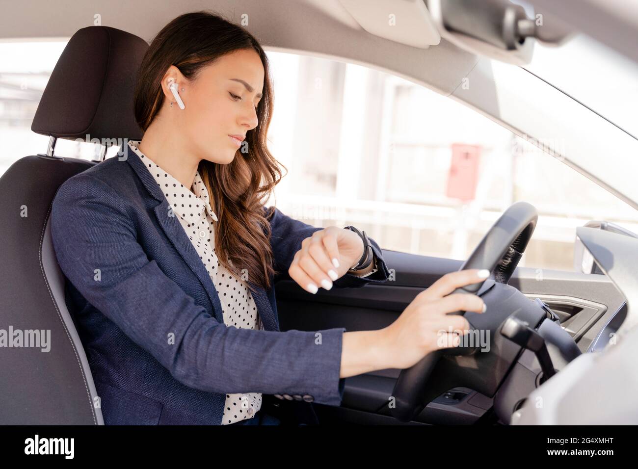 Female entrepreneur checking time while driving car Stock Photo - Alamy