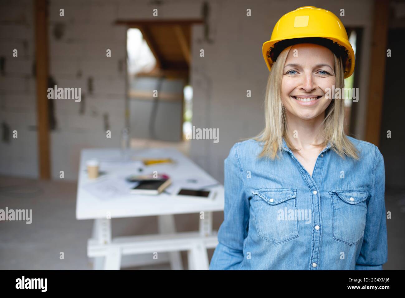 Smiling female contractor wearing hardhat at construction site Stock ...