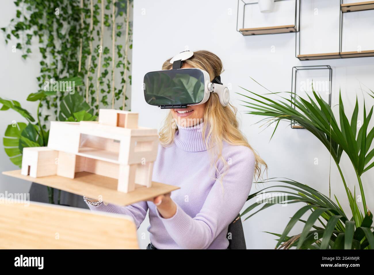 Smiling female professional wearing virtual reality simulator holding ...
