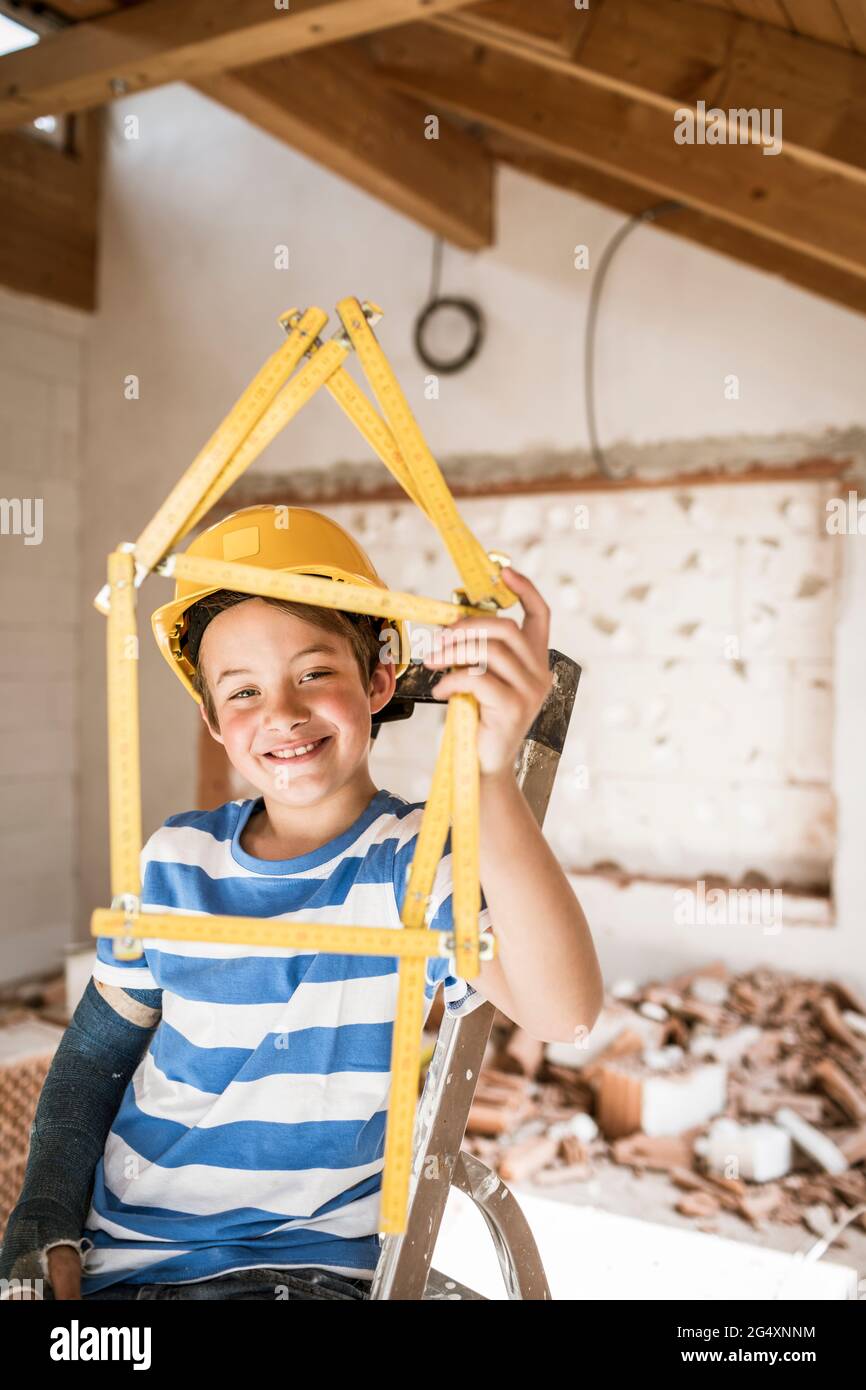 Boy making house shape through tape measure during rebuilding house ...