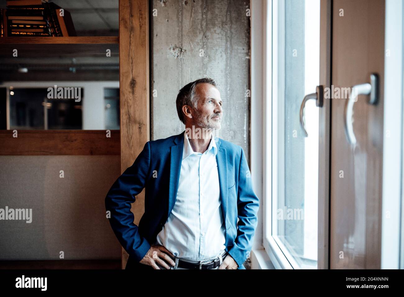 Thoughtful senior businessman looking through window at office Stock ...