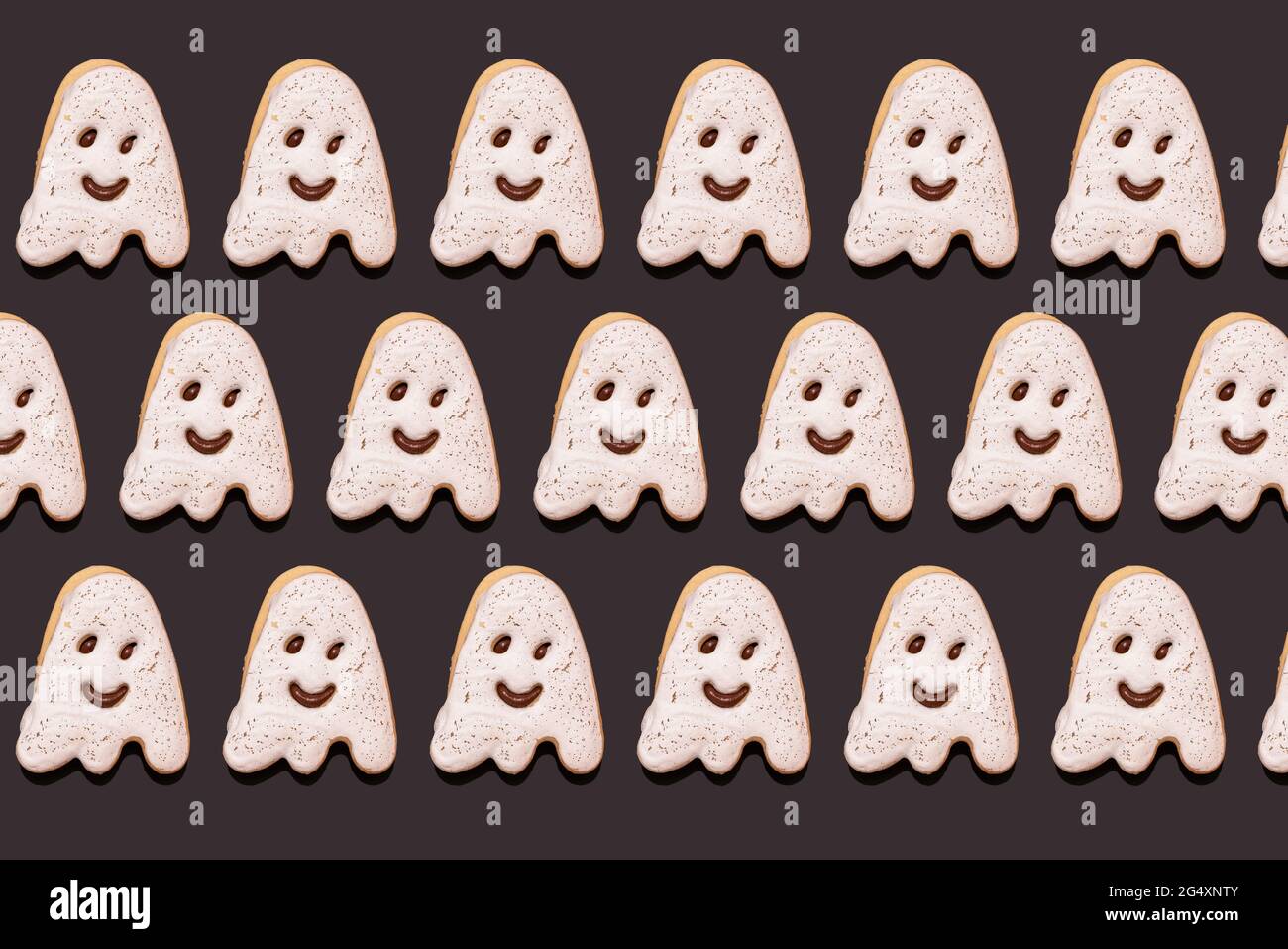 Pattern of ghost-shaped chocolate cookies flat laid against black ...