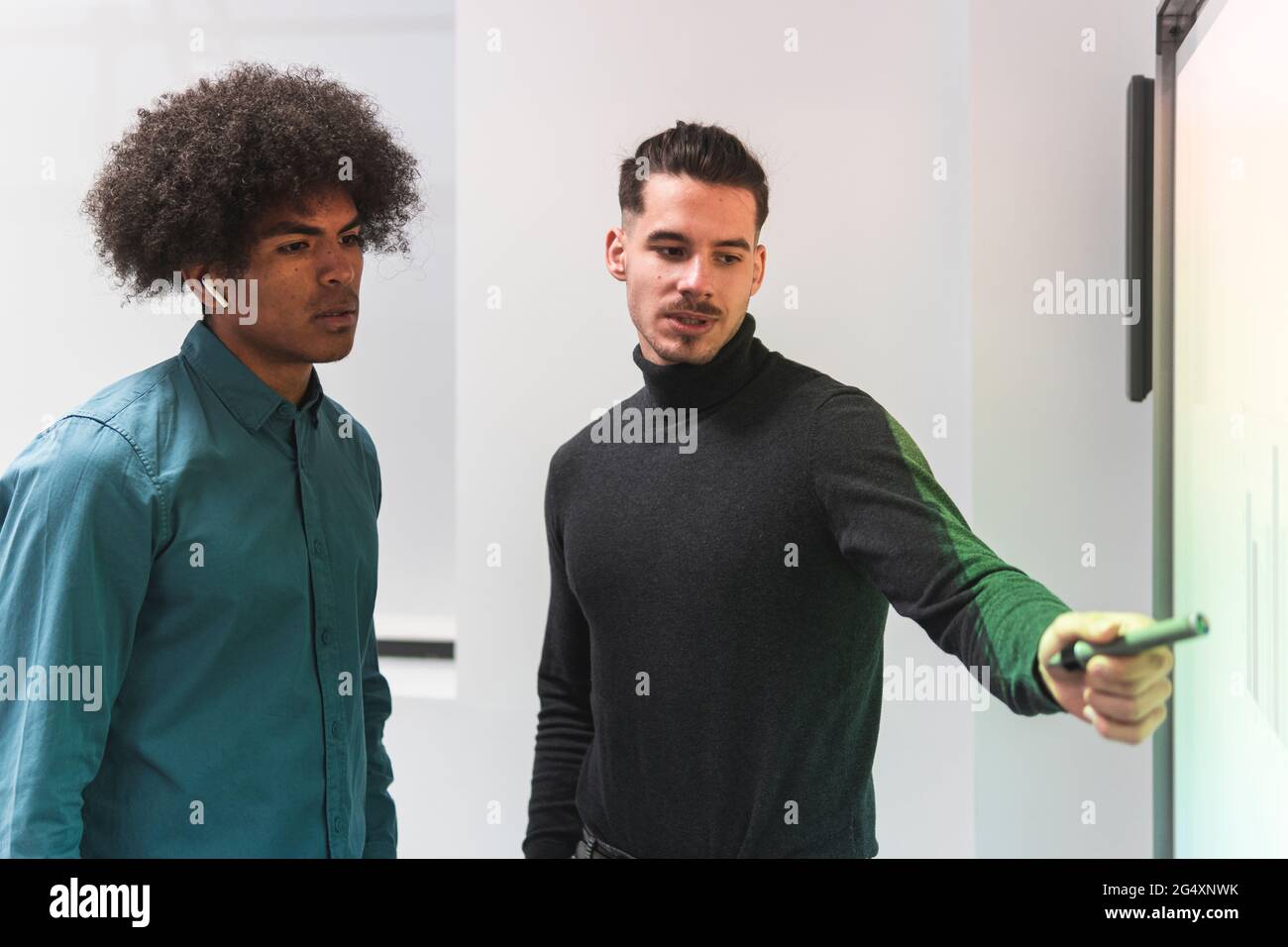 Young male professional explaining colleague on projection screen at ...