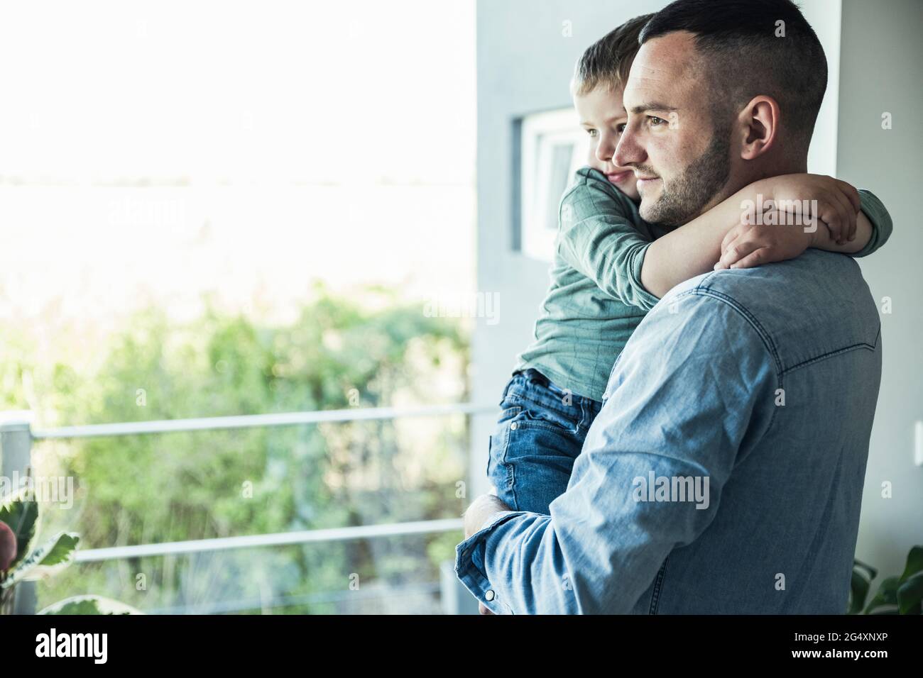 Father carrying son standing in balcony while looking away Stock Photo ...