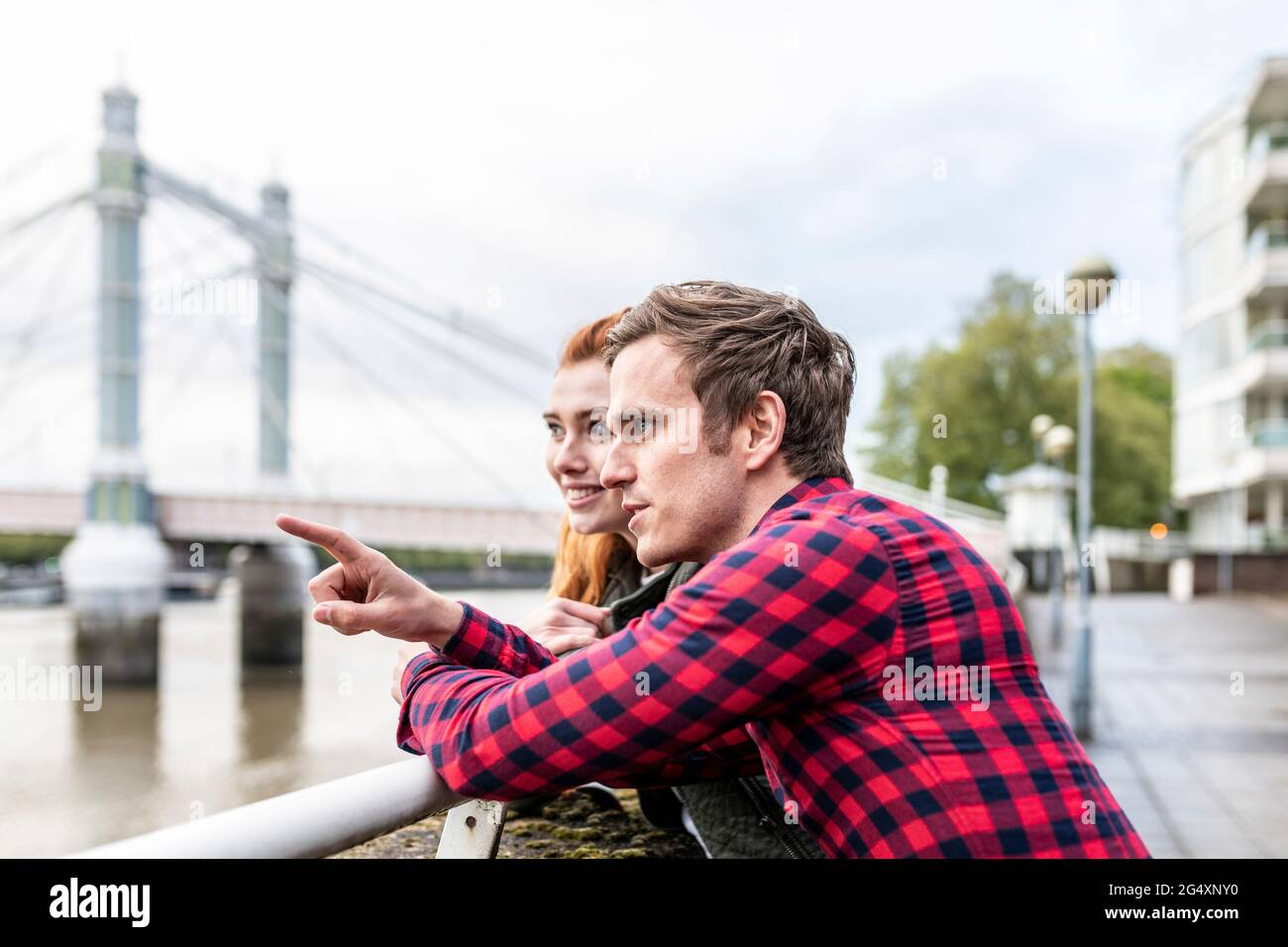 Man pointing while leaning on railing with girlfriend Stock Photo - Alamy