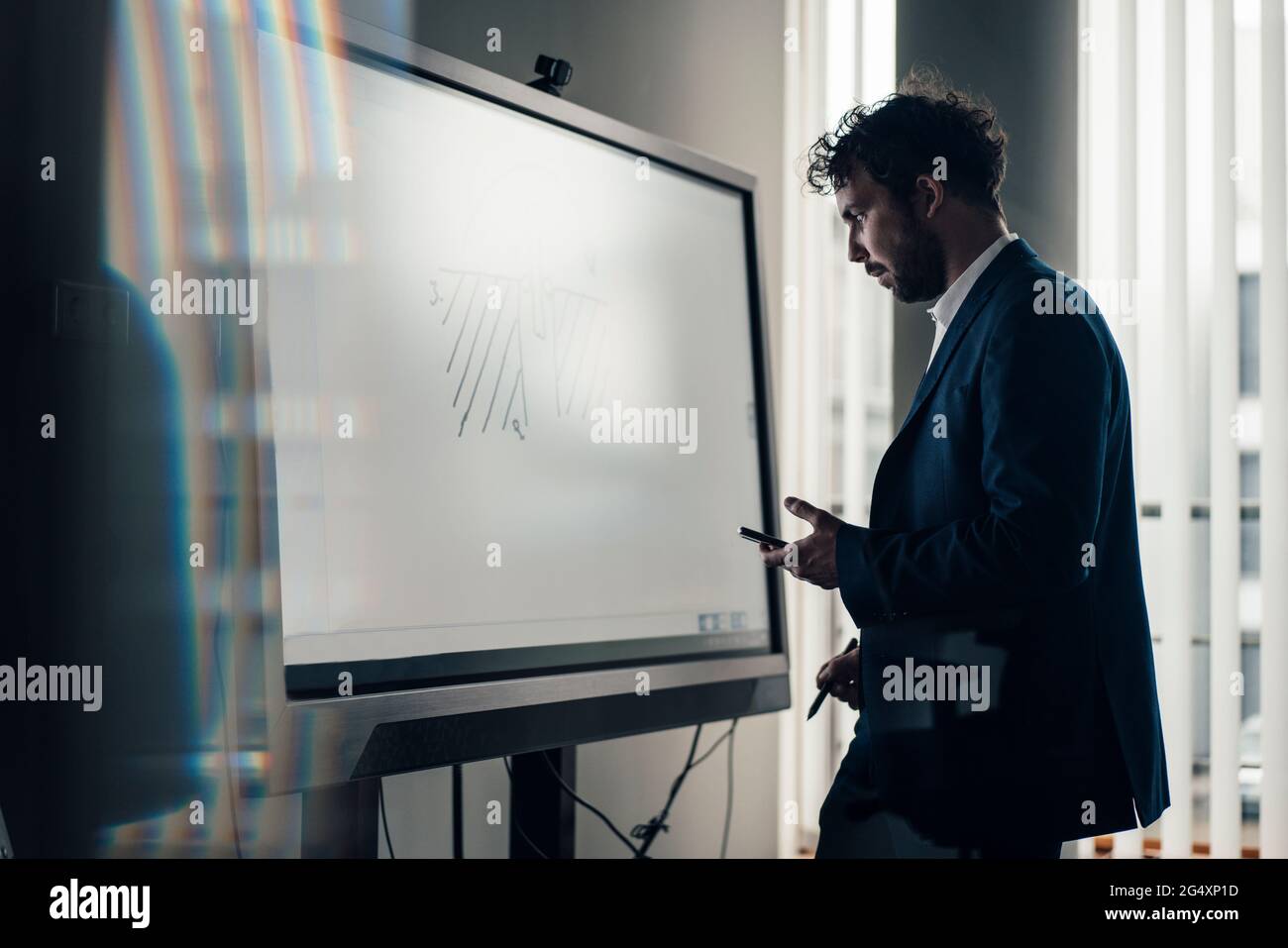 Male entrepreneur looking at diagram on projection screen in office ...