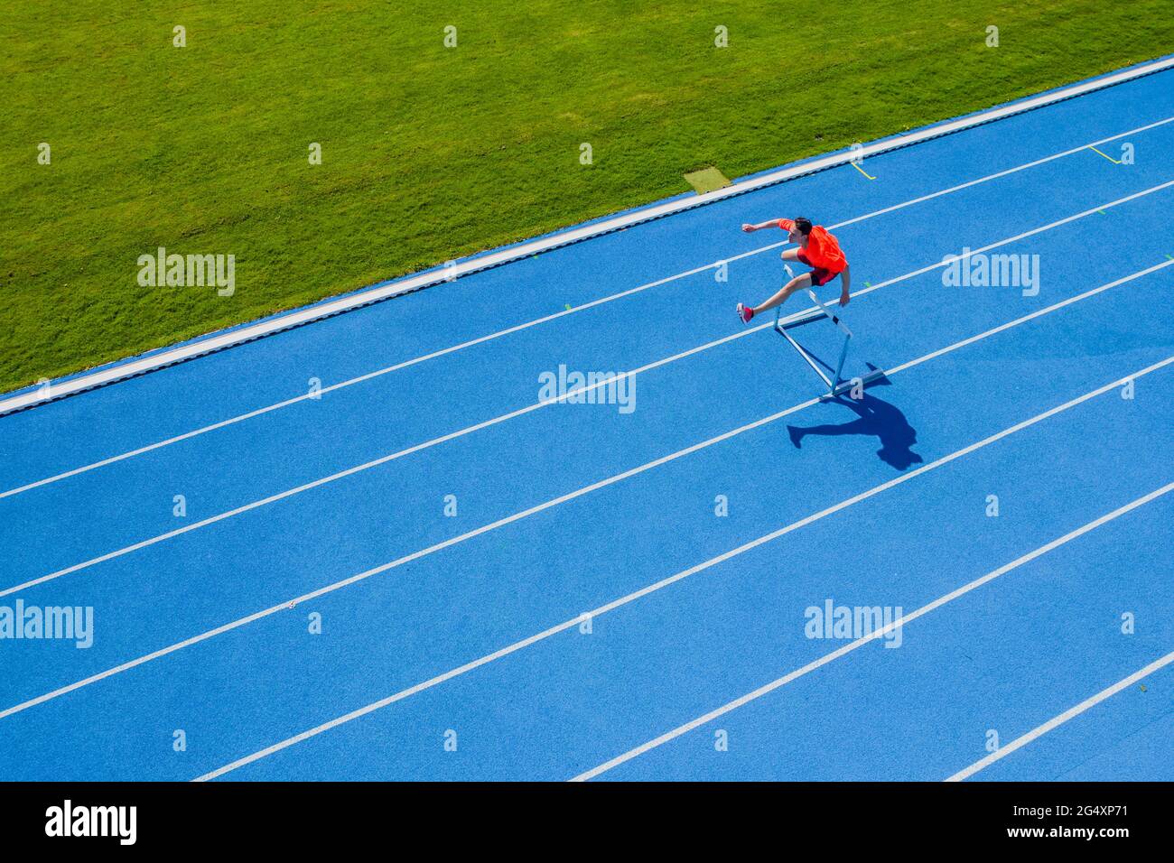 Young man jumping over hurdle Stock Photo - Alamy