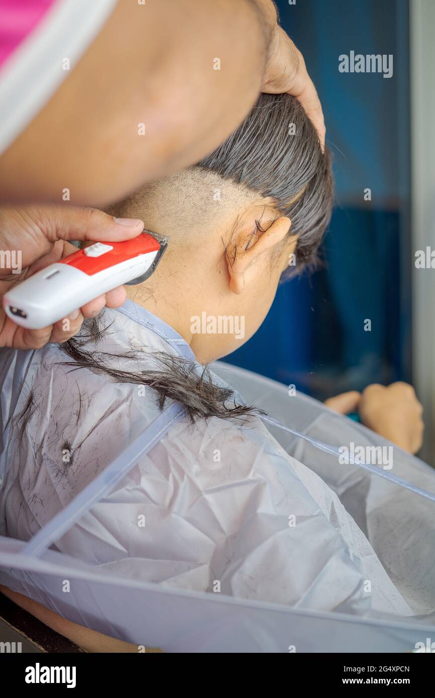 Asian child getting haircut at home from the father. Young boy save his ...