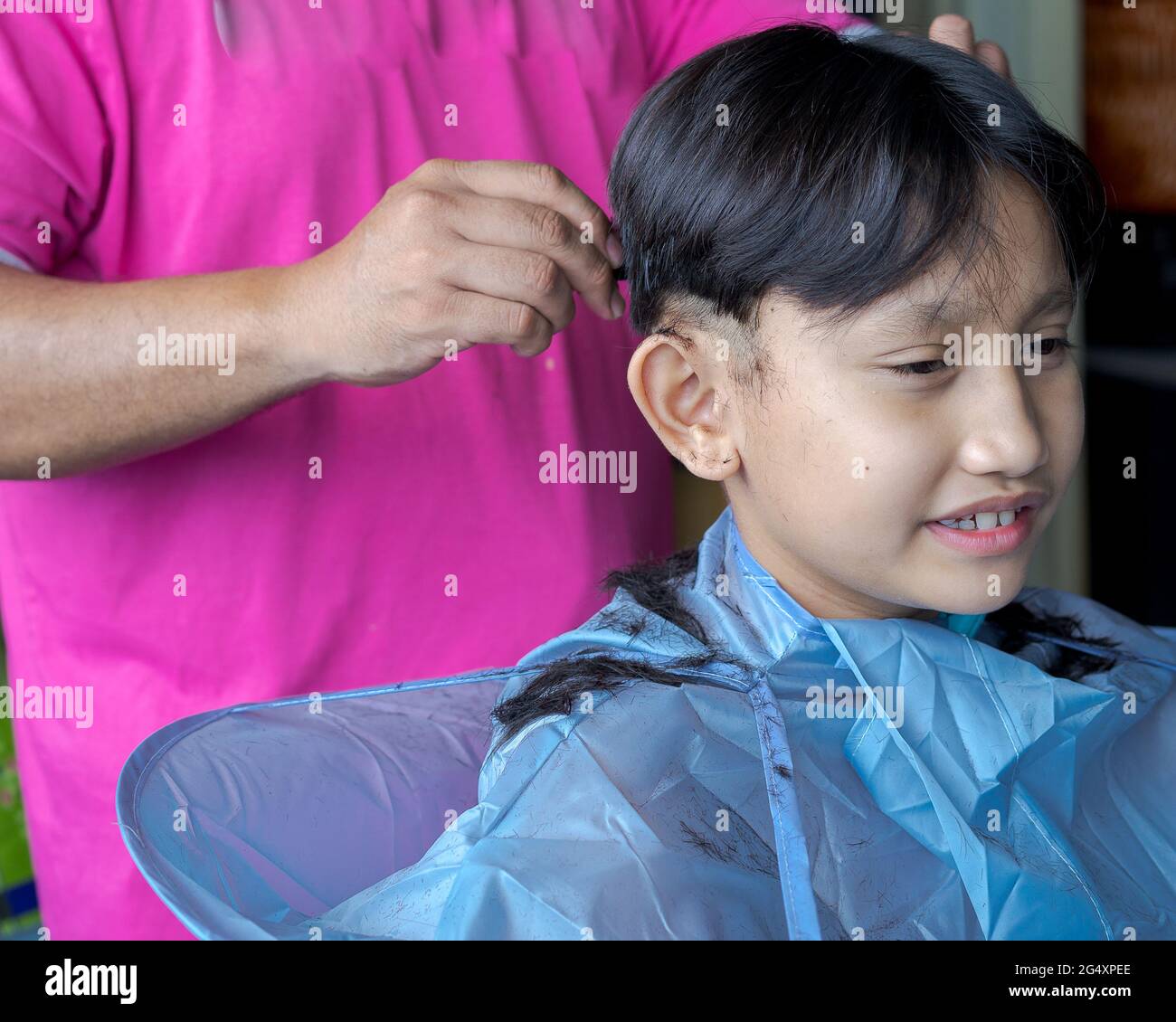 Asian child getting haircut at home from the father Stock Photo - Alamy