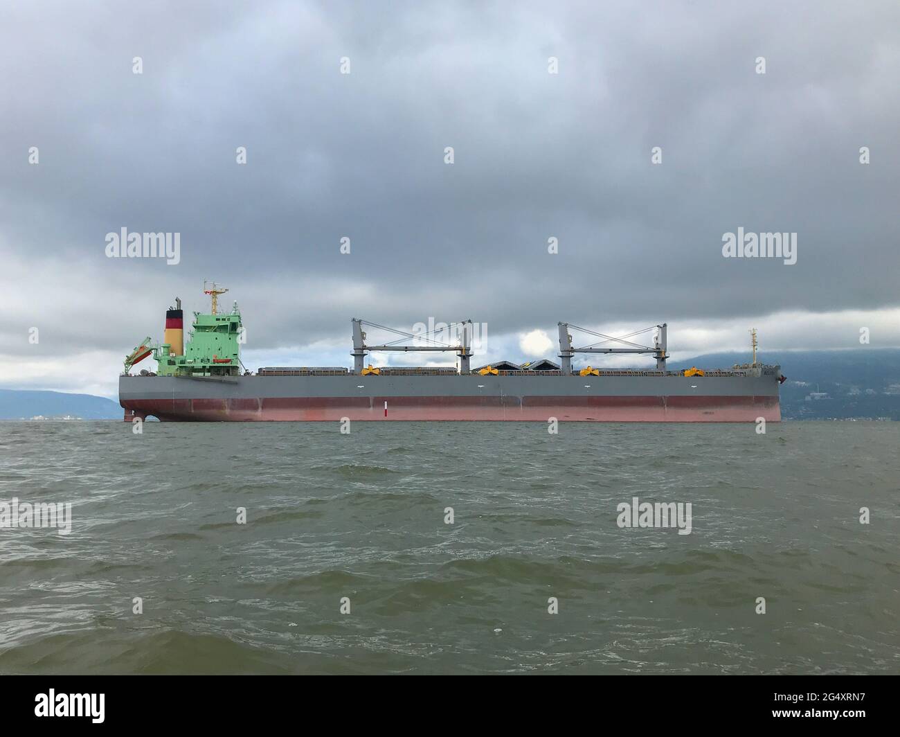 Freight ship cargo vessel at anchor in shore Stock Photo - Alamy