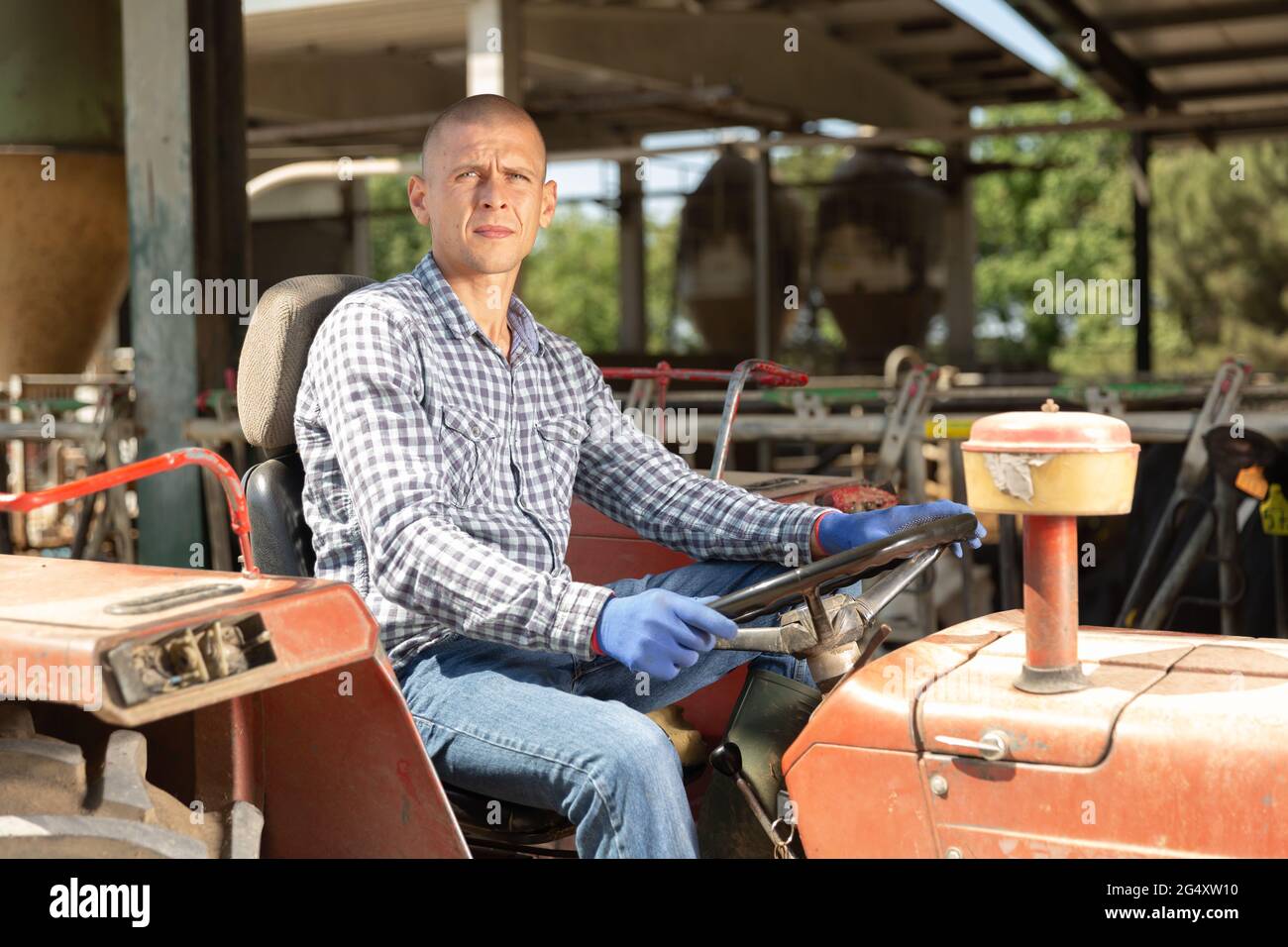 Hardworking young man on a farm sitting behind the wheel of a ...