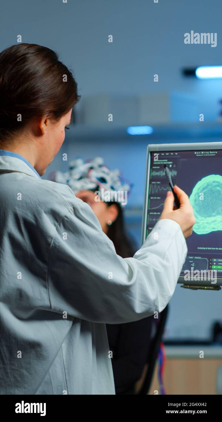 Researcher looking at monitor analysing brain scan while coworker ...