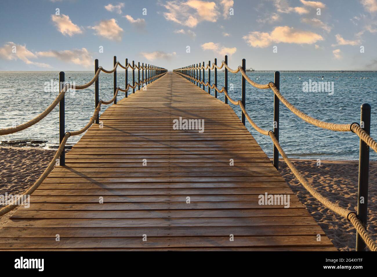 Wooden pier extending into the sea at sunrise Stock Photo - Alamy