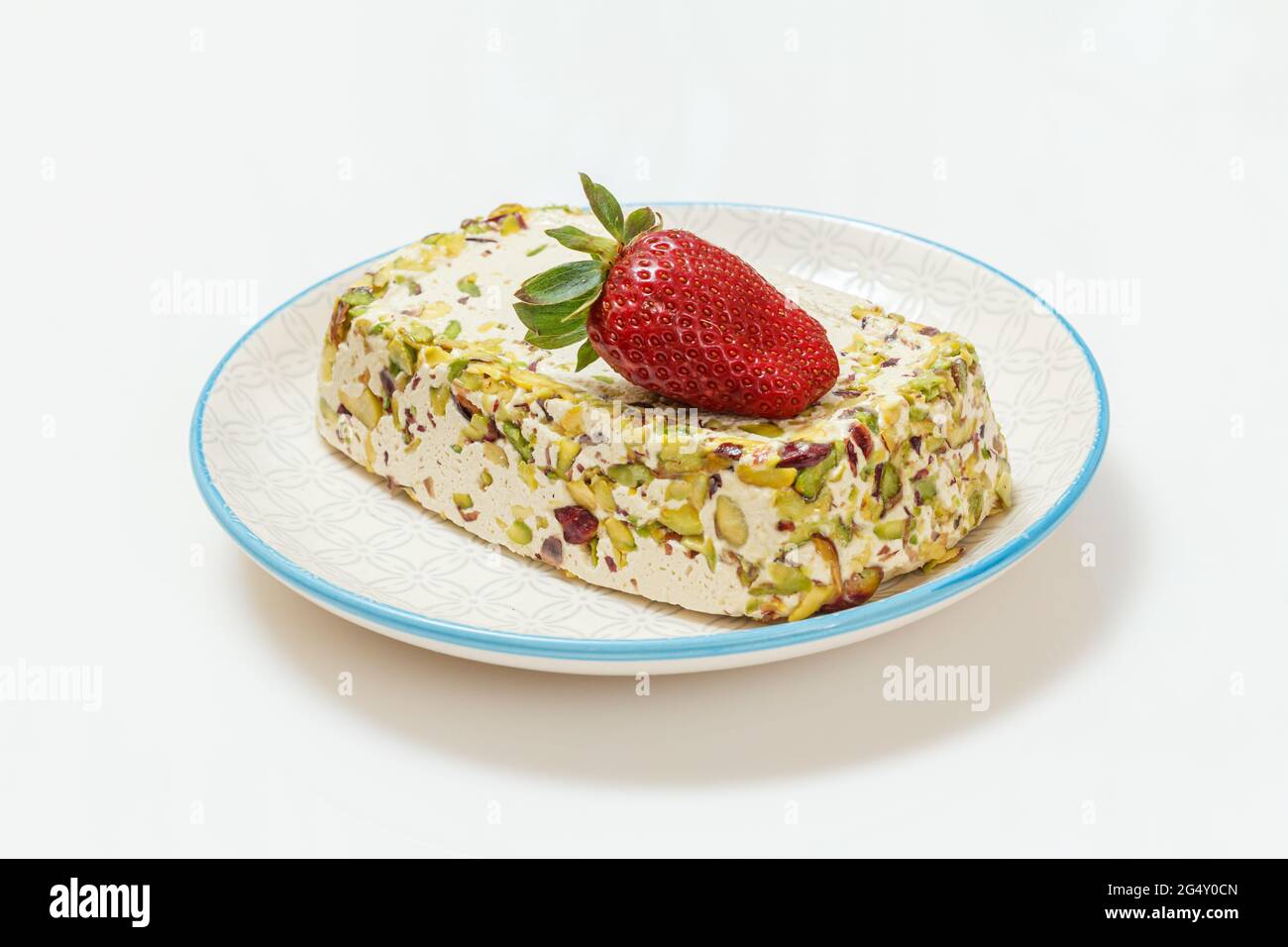 Halva with pistachios on plate on white background Stock Photo - Alamy