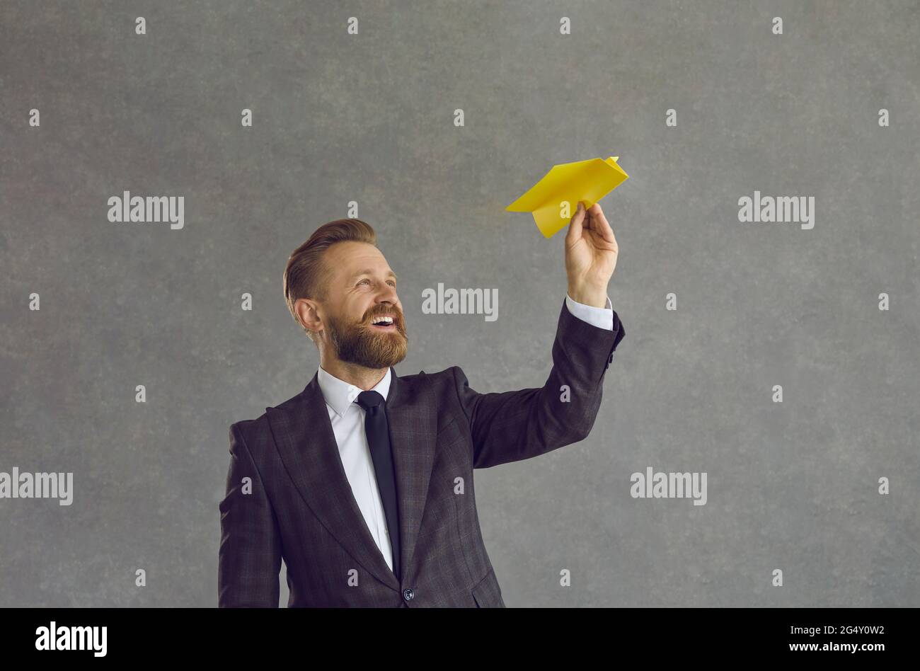 Happy young business executive flying paper plane standing isolated on ...