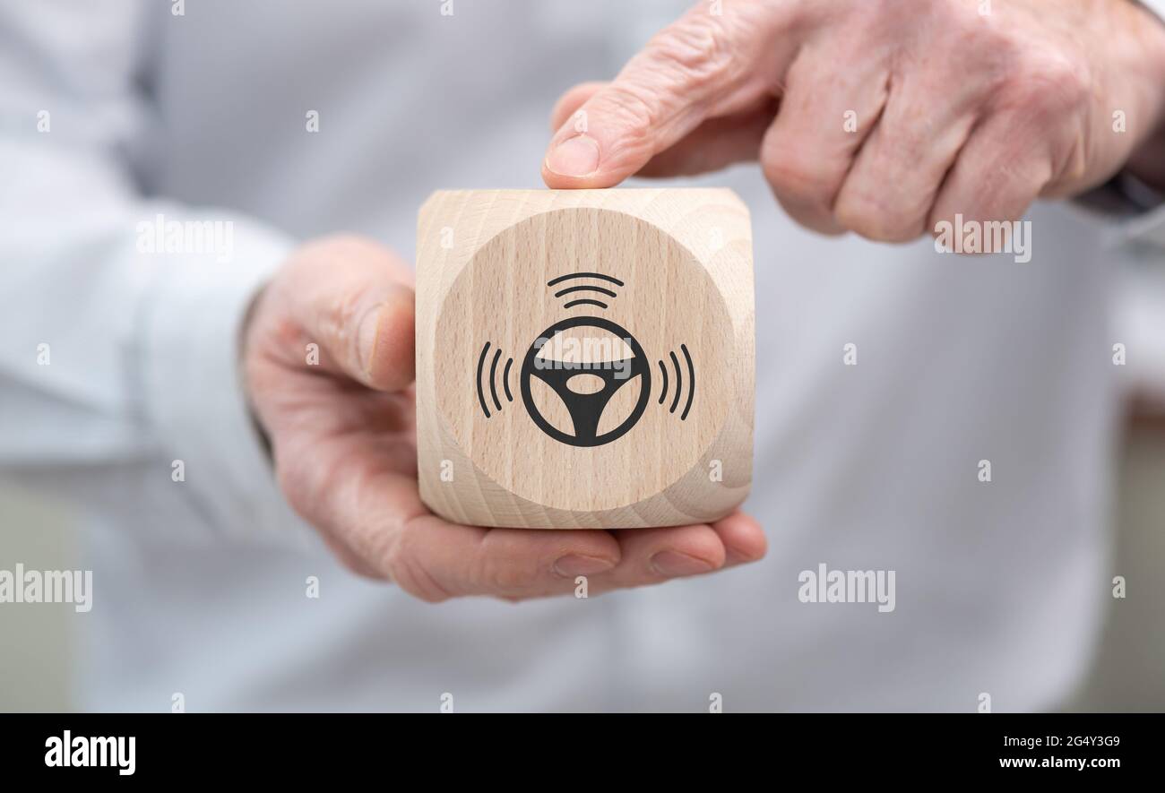 Hand holding a wooden cube with symbol of self-driving car concept ...