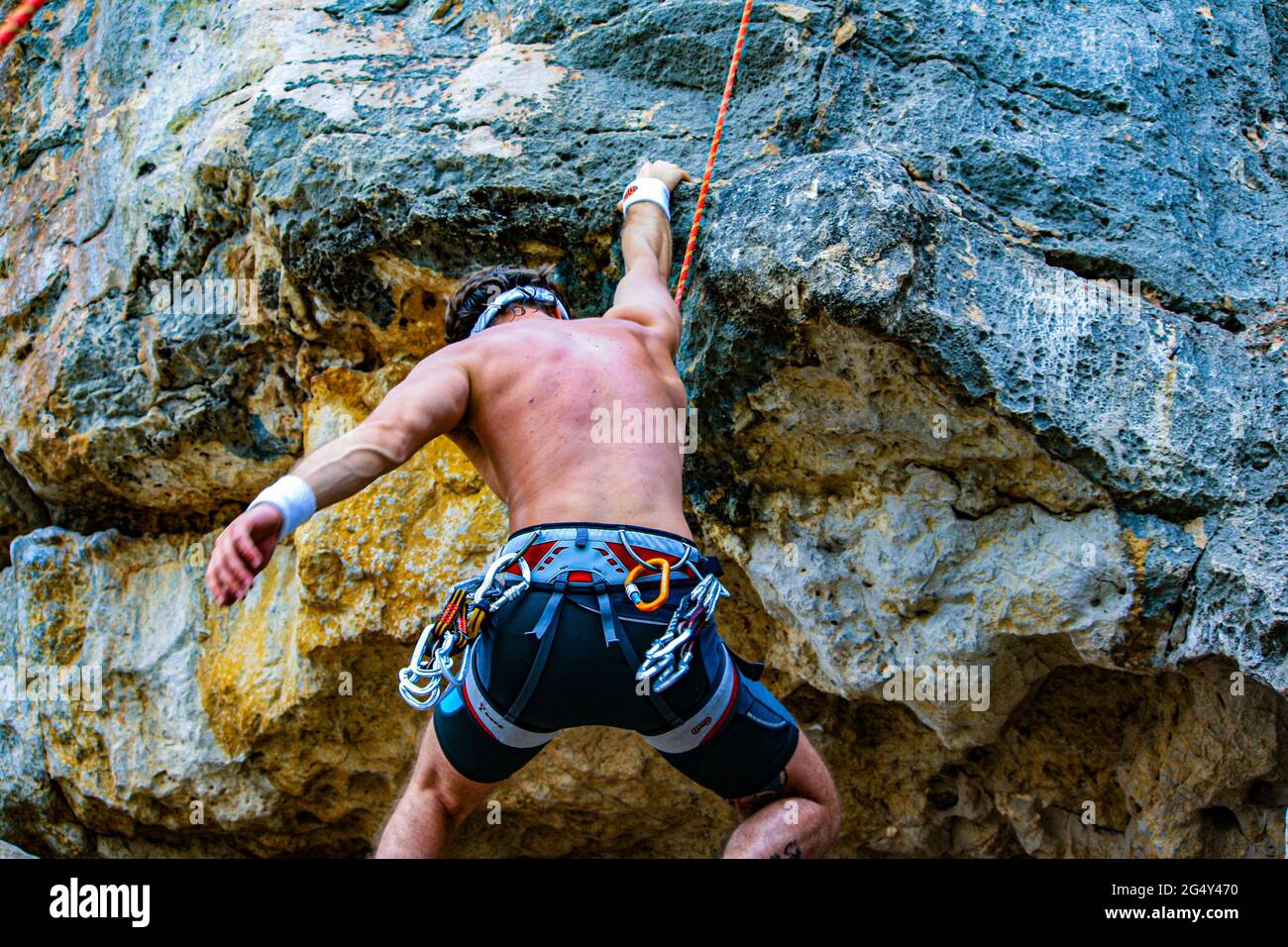 climbing. man holds one hand to the rock in suspense while climbing the ...