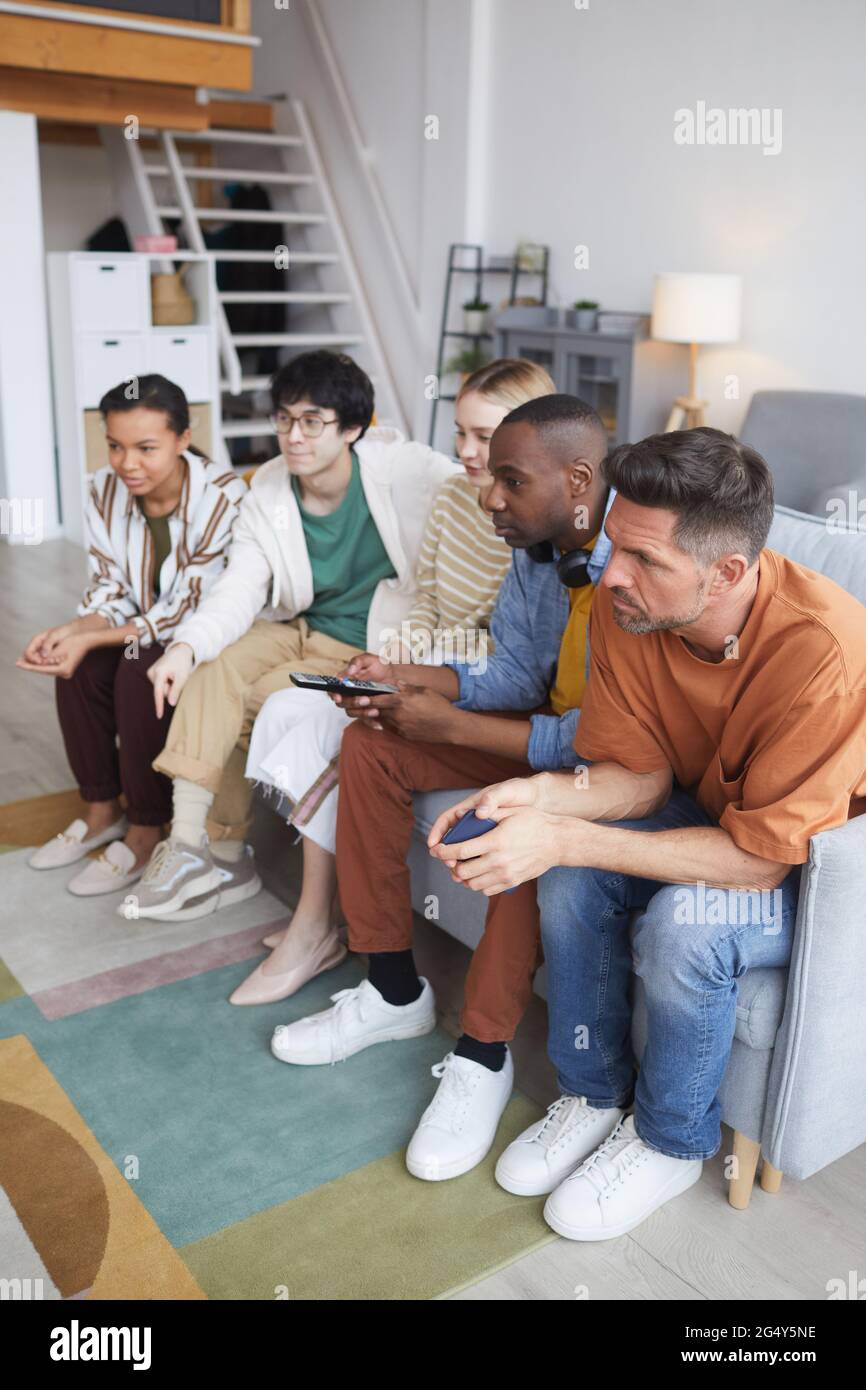 Vertical full length view at diverse group of friends watching TV at ...