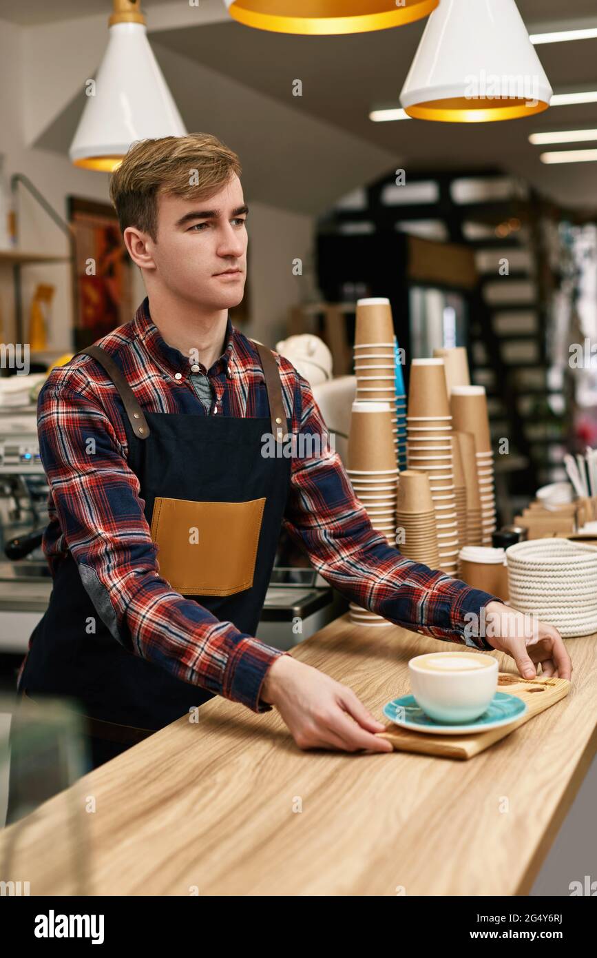 happy male waiter in apron holding cup of hot drink Stock Photo - Alamy