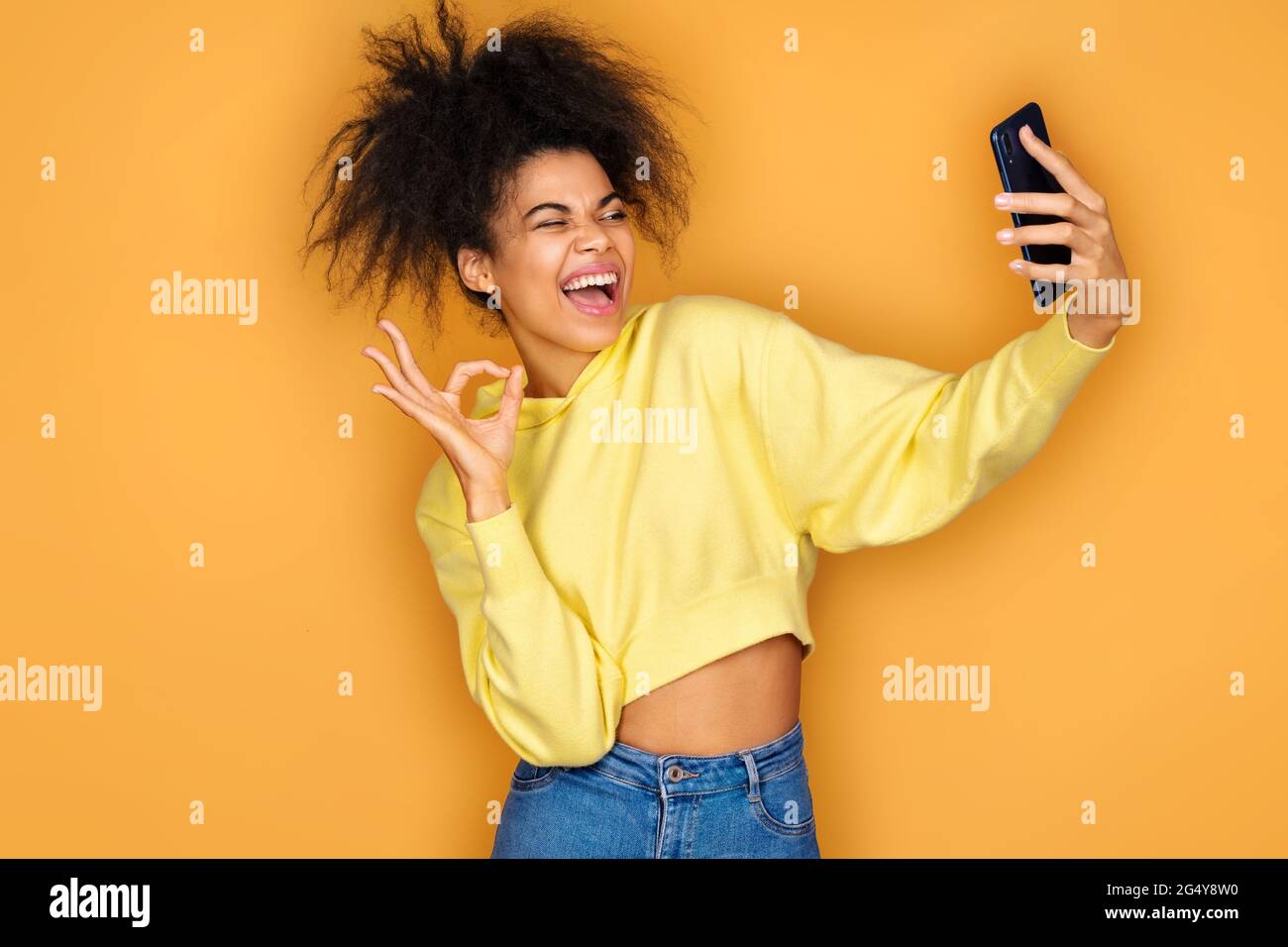 Young girl takes selfie photo and makes okay gesture, smiles at camera ...
