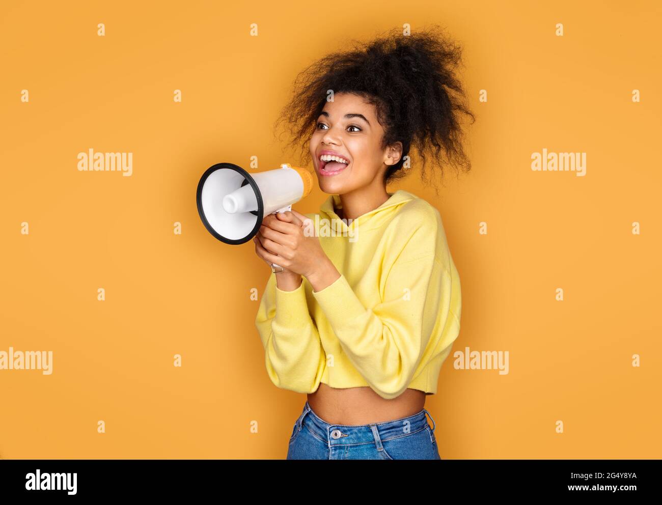 Happy girl shouts in megaphone. Photo of african american girl on ...