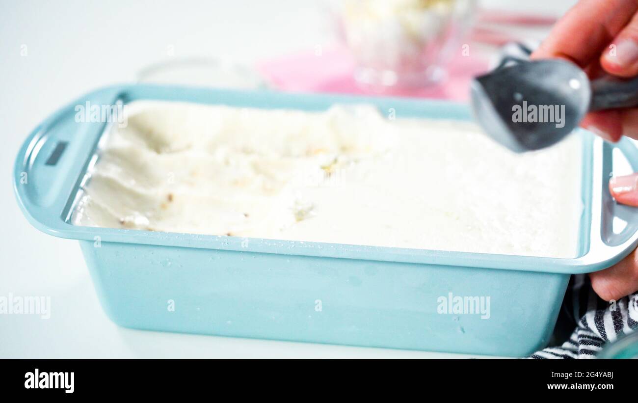 Scooping homemade coconut ice cream into a glass ice cream bowl Stock ...