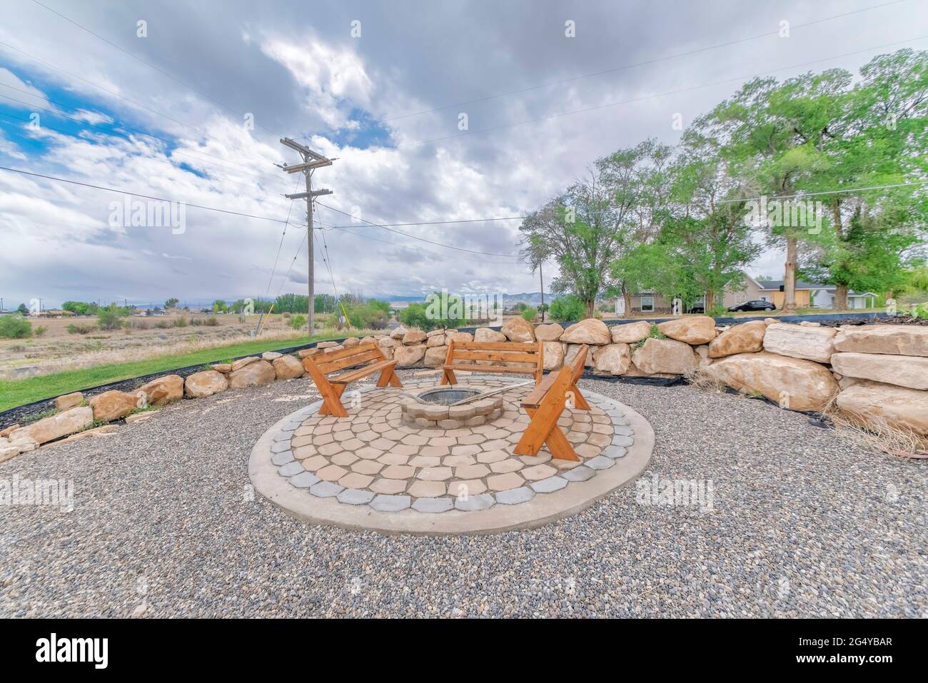 Outdoor rest area with wooden seat around a firepit surrounded with ...