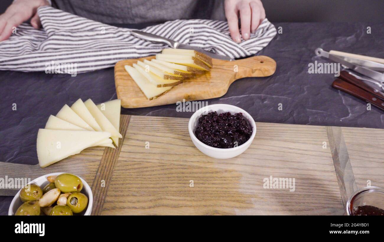 Arranging gourmet cheese, crakers, and fruits on a board for a large ...