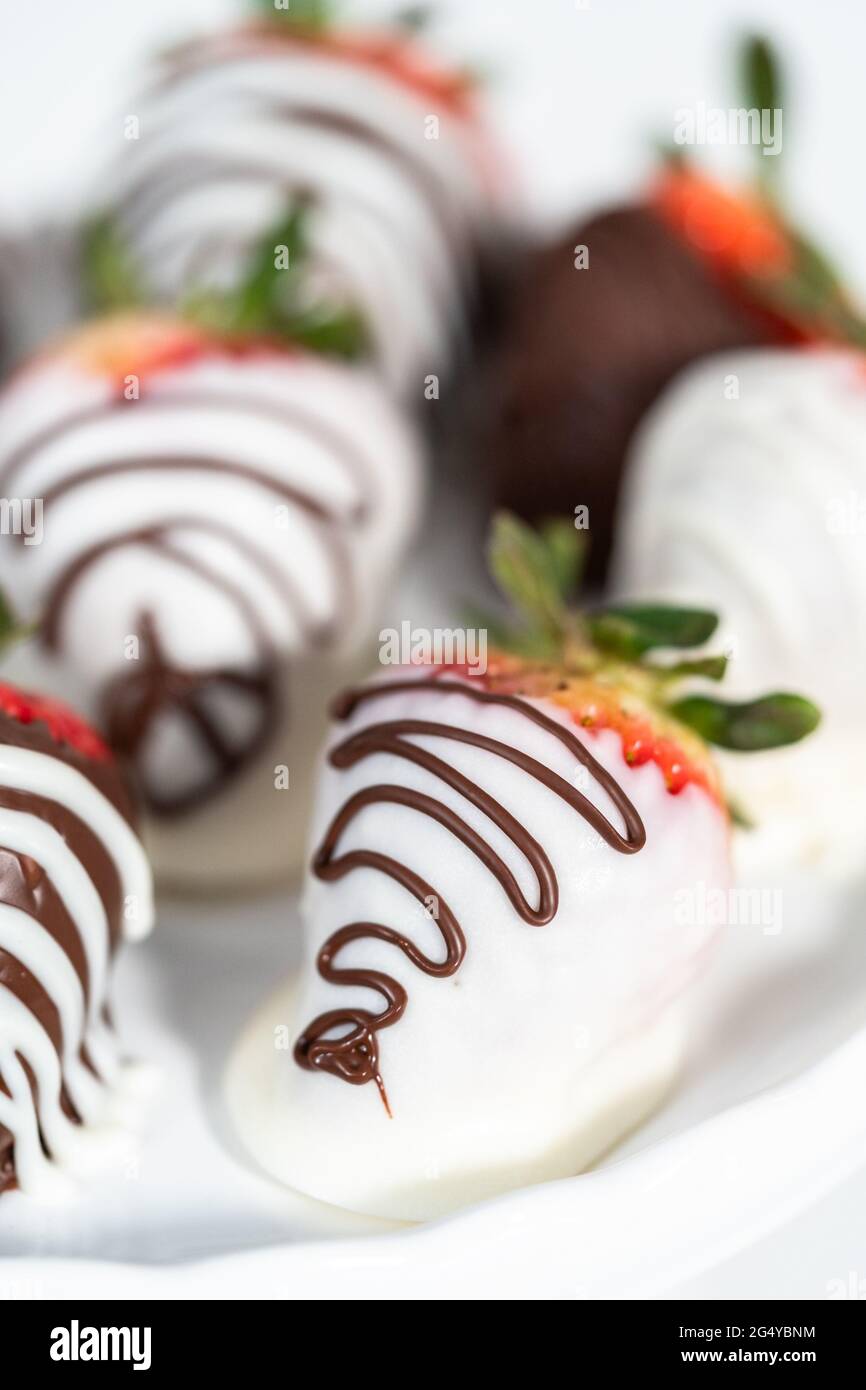 White and dark chocolate dipped strawberries on a white cake stand ...