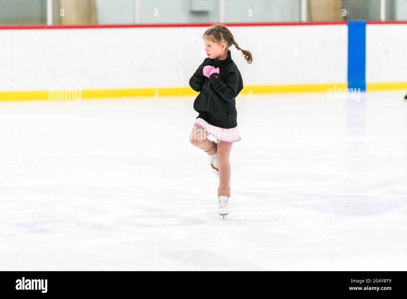 Little girl practicing figure skating on an indoor ice skating rink ...