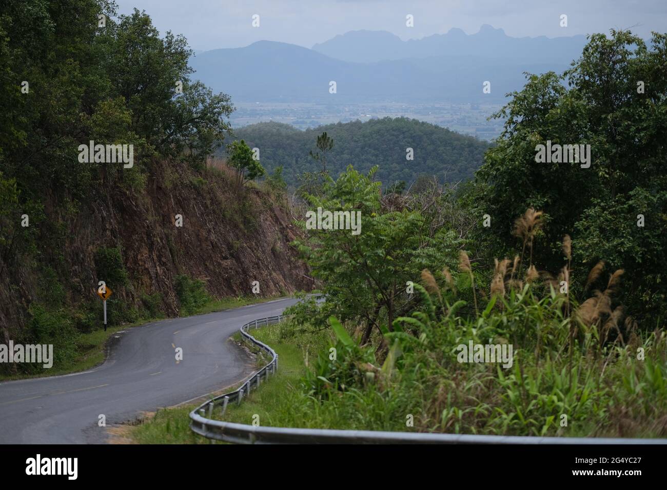 A twisted road is going downhill in front of idyllic landscape of ...
