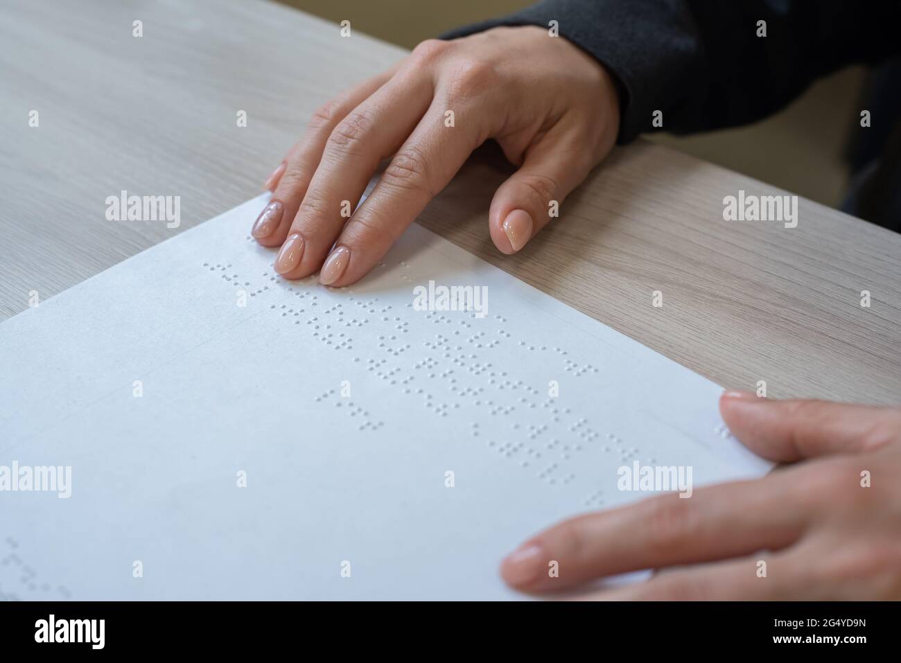 Close-up woman reads the text to the blind. Woman's hands on paper with ...