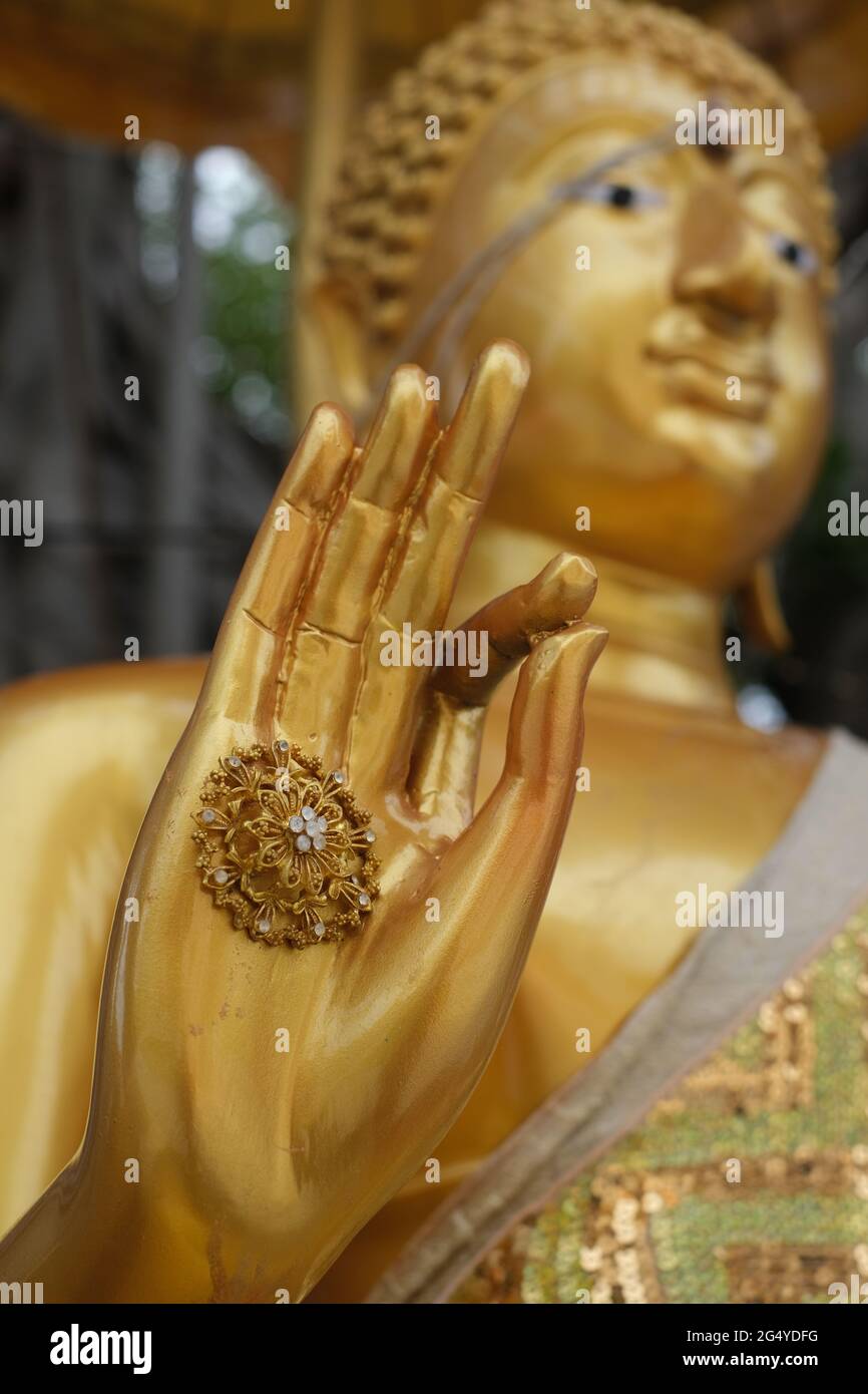 Hand of Buddha's statue giving blessing, with some jewelery and blurred ...