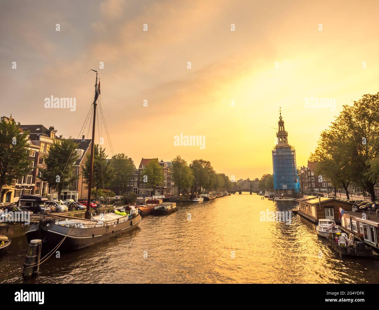 Constructed clock tower along canal in Amsterdam with evening light sky ...