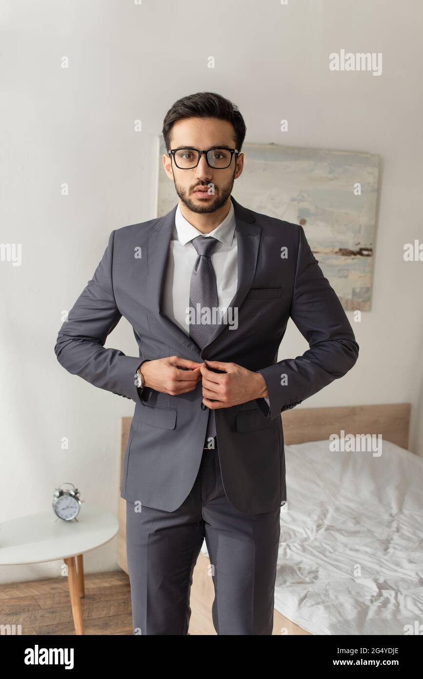 Bearded businessman buttoning jacket in bedroom at home Stock Photo - Alamy