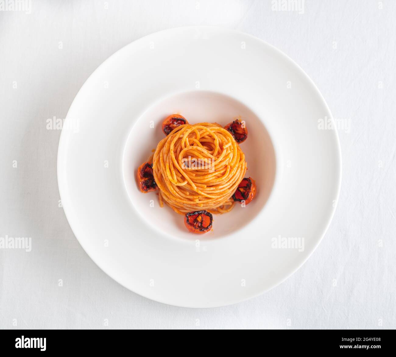A bowl of spaghetti with burned tomatos and shredded basil Stock Photo ...